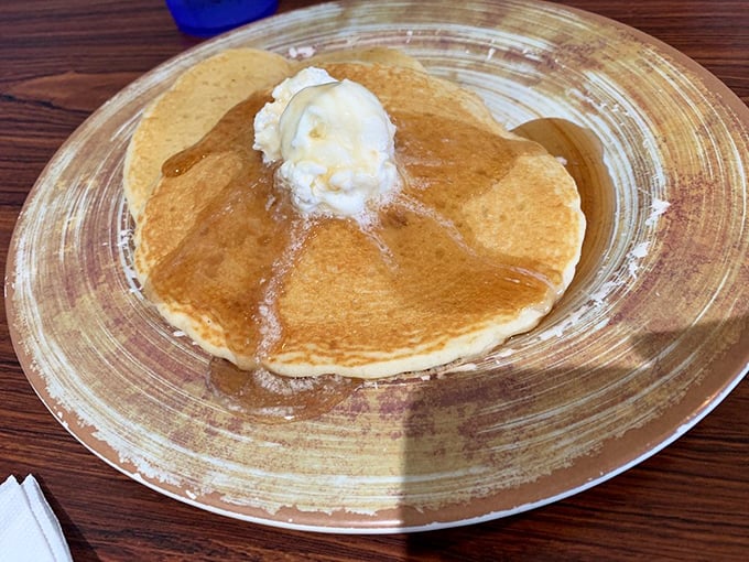 Golden pancake perfection with melting butter creating its own little maple syrup swimming pool—breakfast architecture at its finest.