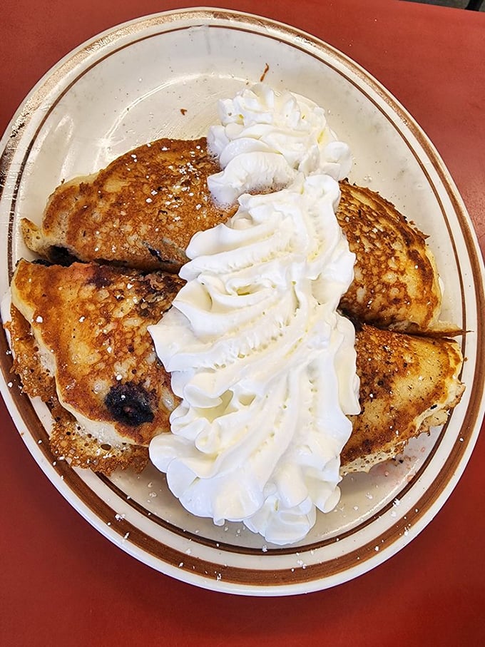 Blueberry pancakes crowned with a cloud of whipped cream—proof that sometimes the best things in life come stacked and ready for syrup.