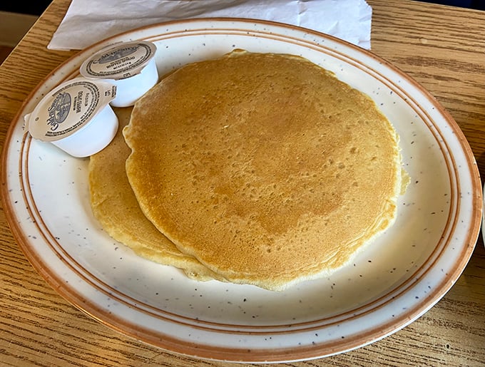 Pancakes so perfectly golden they belong in Fort Knox. Simple, unpretentious, and exactly what pancakes should be—a blank canvas for syrup rivers and butter lakes.