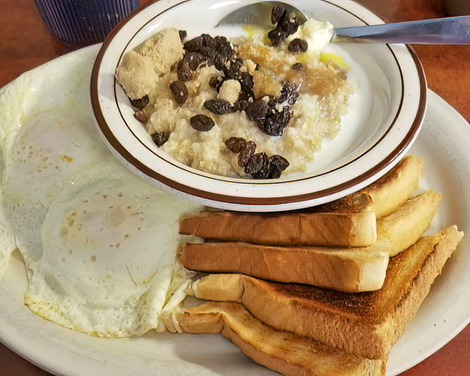 Eggs, toast, and what appears to be grits with raisins – a breakfast trinity that proves sometimes the simplest combinations deliver the most profound satisfaction.