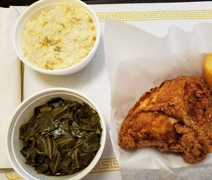 Soul food trinity: tender collard greens, creamy potato salad, and that chicken—crispy on the outside, juicy within—a holy experience for your taste buds.