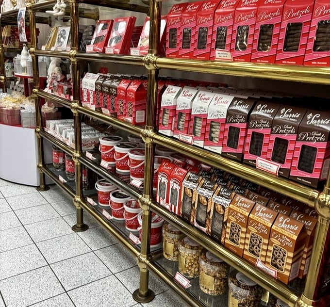 Brass railings and red packaging create a chocolate library where every volume tells a delicious story. The pretzel section deserves its own card catalog.