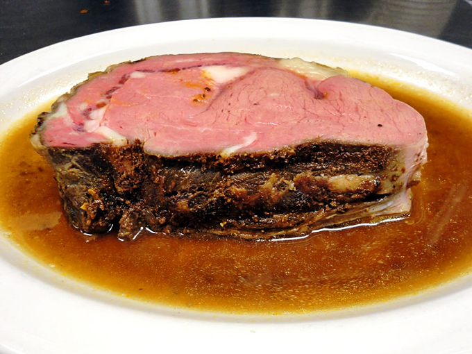 Prime rib cooked to a perfect medium-rare, swimming in its own savory juices. The rosy interior promises buttery tenderness with each bite.
