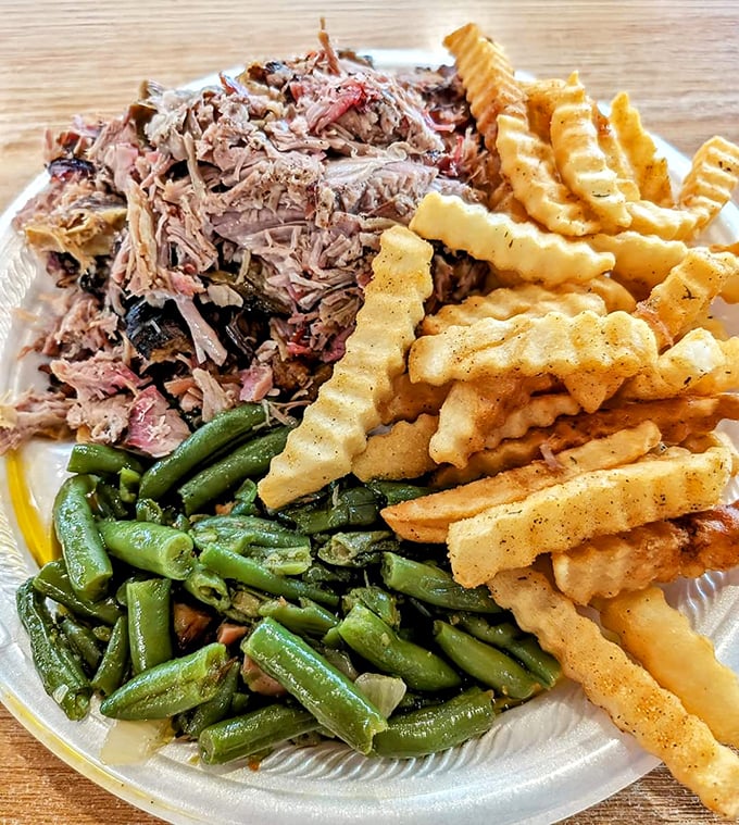 A barbecue trinity: tender pulled pork with a smoke ring that would make pitmasters weep, crispy fries, and green beans that didn't come from a can.