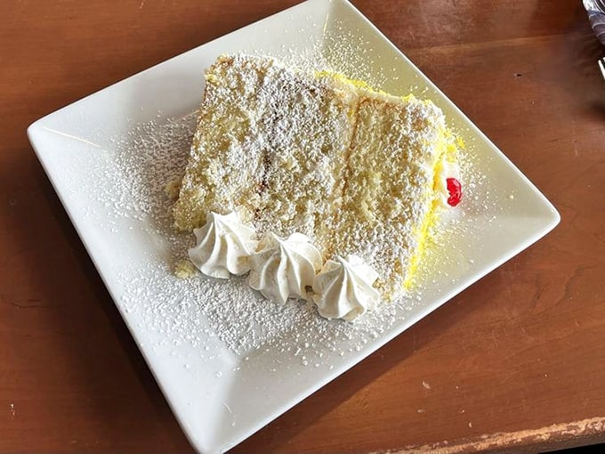 A slice of heaven masquerading as cake—light, airy, and dusted with powdered sugar that falls like delicious snow.