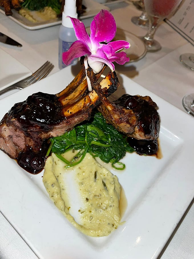 These lamb chops wear their glaze like a designer outfit, topped with an orchid that's both garnish and crown. The mashed potatoes look cloud-soft and herb-flecked.