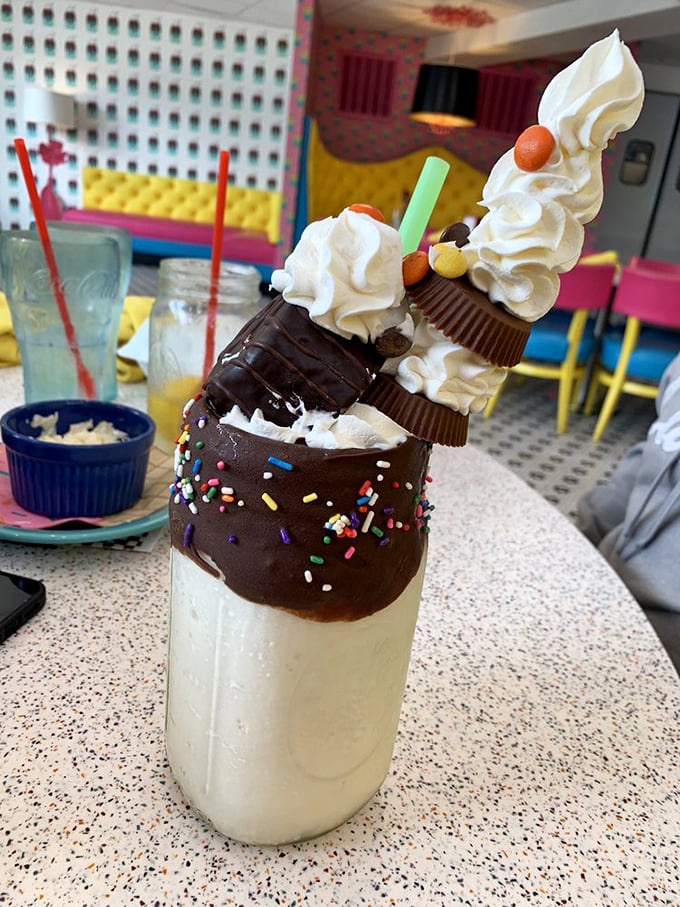 Dessert architecture at its finest! Chocolate-dipped rim, towering whipped cream, candy garnishes—this milkshake isn't just a drink, it's performance art you can consume. 