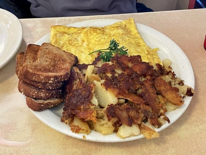 A perfectly cooked omelet with toast and hash browns—the holy trinity of diner breakfast, executed with the precision of a culinary sonnet.