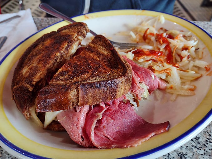 The Reuben sandwich – where thinly sliced corned beef meets sauerkraut in a dance so perfect it deserves its own Broadway show, with hashbrowns playing supporting role.