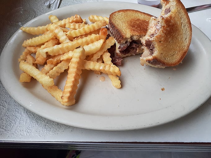 That half-eaten Reuben tells the whole story—crispy grilled rye, melted cheese, and the kind of satisfaction that requires no filter or hashtag.