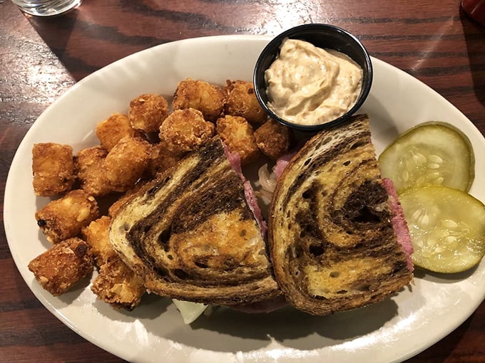 The Reuben sandwich—where marble rye meets its destiny. Served with crispy tots and pickles that add the perfect tangy counterpoint.