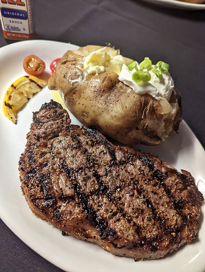 A perfectly charred ribeye alongside a loaded baked potato—proof that sometimes the simplest pleasures in life are also the most satisfying.