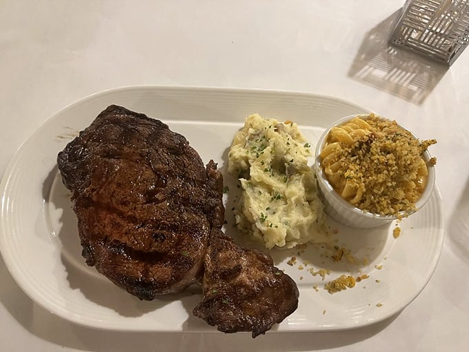 A perfectly seared steak with sides of mashed potatoes and that legendary mac and cheese—the holy trinity of steakhouse perfection.