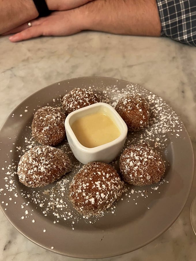Ricotta fritters dusted with powdered sugar surround a pool of custard – like delicious little planets orbiting a sweet sun.