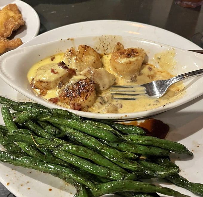 Scallops seared to caramelized perfection swim in a creamy sauce alongside vibrant green beans—proof that small-town Ohio knows seafood.