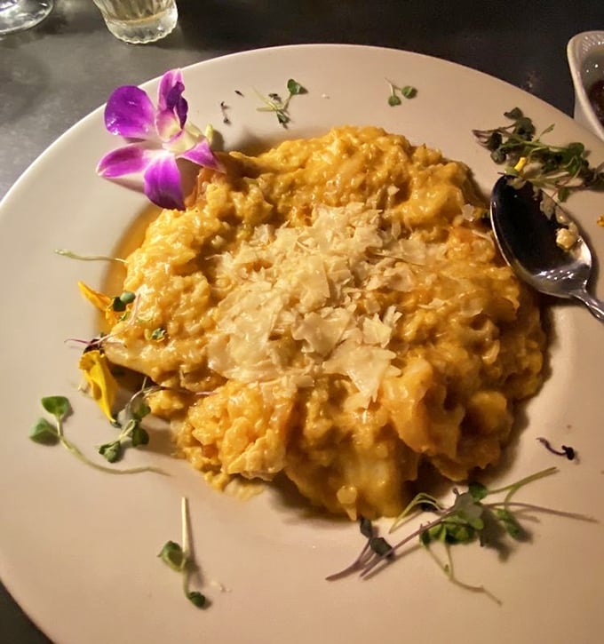Risotto that doesn't just sit on the plate but performs there, dressed up with a purple orchid like it's heading to the culinary Oscars.