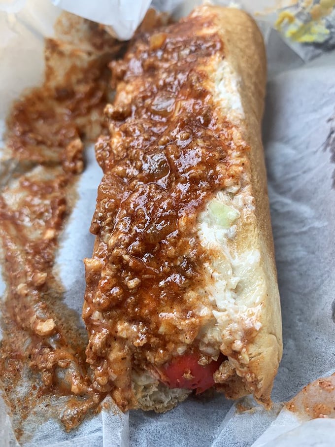Behold the slaw dog in its natural habitat—simple white paper, ready to deliver that perfect hot-cold contrast that makes taste buds sing.