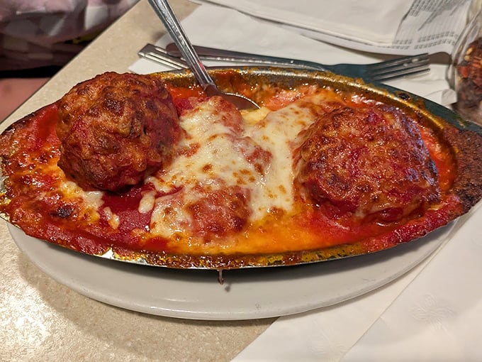 These meatballs aren't just big—they're the size of your ambitions on a good day, swimming in a sauce that's been simmering since your morning alarm went off.