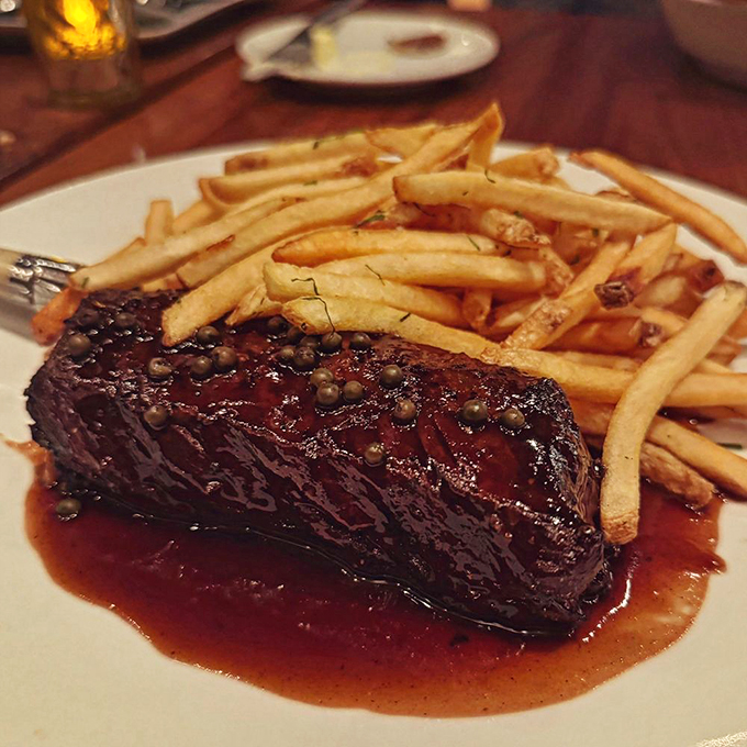 This isn't just steak frites—it's therapy on a plate. The glistening peppercorn sauce makes a compelling case for licking the plate when nobody's watching.
