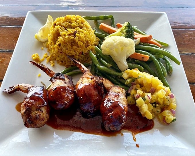 Bacon-wrapped shrimp nestled among colorful vegetables and saffron rice—proof that sometimes the best things in life come in small, delicious packages.