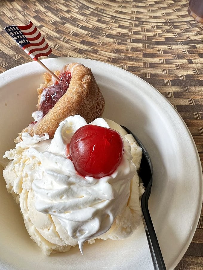 A scoop of vanilla crowned with whipped cream and a cherry, plus a slice of pie—America's dessert dream team in action.