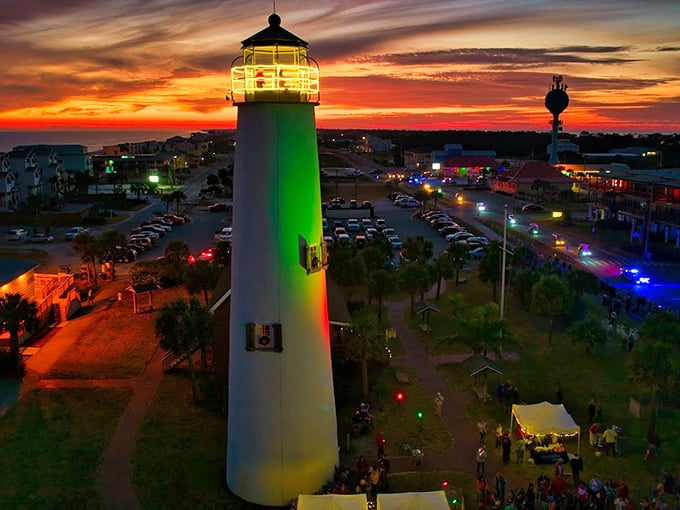The lighthouse glows like nature's mood ring at sunset, casting emerald dreams across the harbor as day surrenders to night.