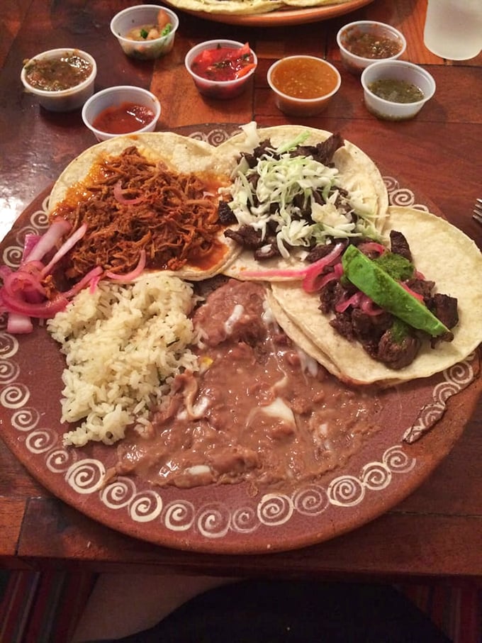 A fiesta on a plate! Multiple taco varieties surrounded by rice, beans, and a rainbow of salsas—proof that variety truly is the spice of life.