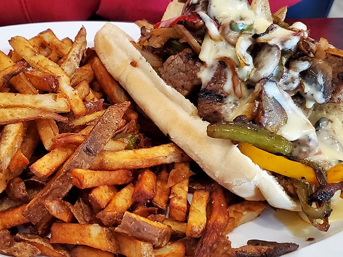 The Philly cheesesteak arrives like a savory work of art—hand-cut fries standing at attention beside a sandwich that demands to be photographed first.