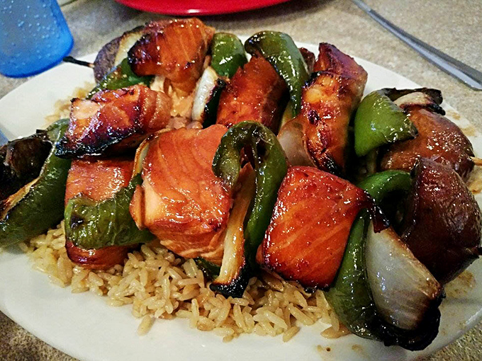 These teriyaki salmon kabobs aren't just dinner—they're edible architecture, with each glazed chunk glistening like jewels atop a rice foundation.