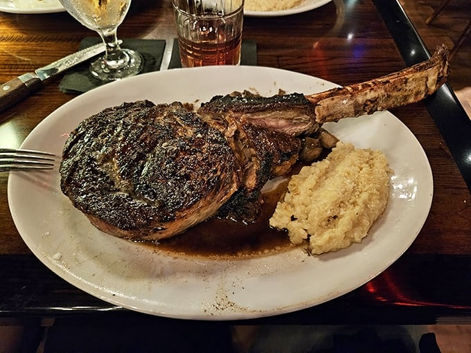 The tomahawk steak arrives like a prehistoric declaration of carnivorous intent—a bone-in masterpiece with a side of mashed potatoes that makes you wonder why anyone would ever choose chicken.