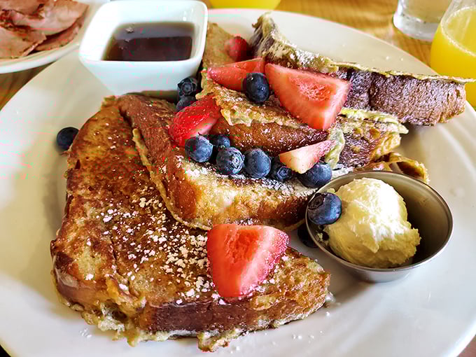 French toast that puts ordinary breakfast to shame—golden challah piled with berries and a scoop of butter melting seductively.