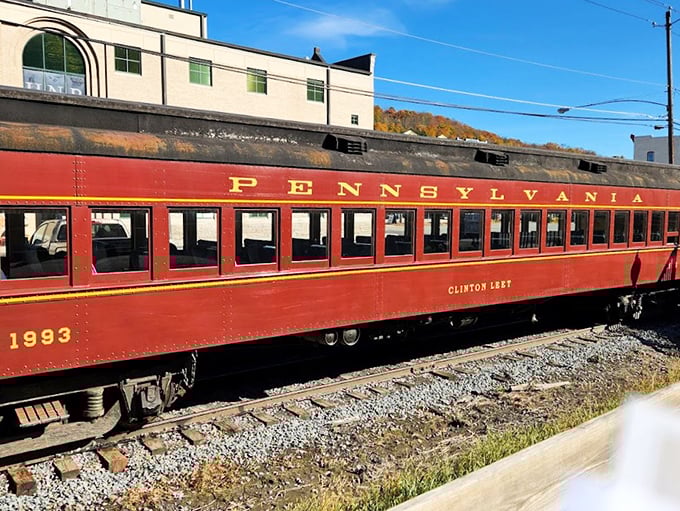 The Clinton Leary coach car, resplendent in Pennsylvania Railroad crimson, waits patiently on the siding—a rolling museum piece that still earns its keep daily.