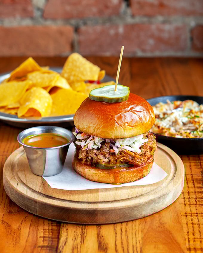 Meet the sandwich that's been breaking hearts across Cincinnati—tender braised pork topped with slaw and a pickle spear standing guard.