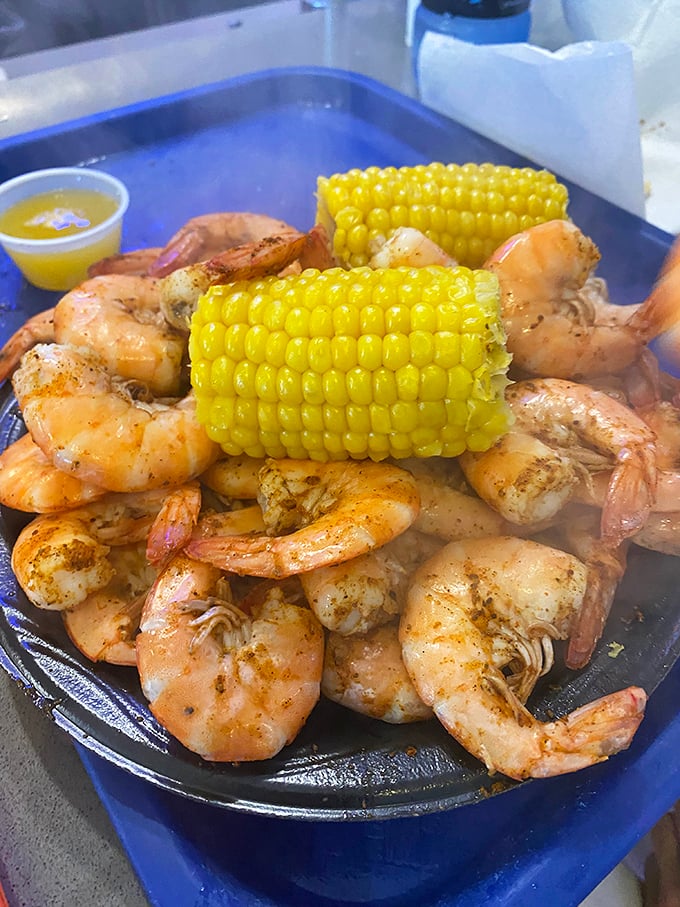 A blue tray of peel-and-eat shrimp with corn on the cob – nature's perfect finger food combo that turns adults into happy, butter-dripping kids again.