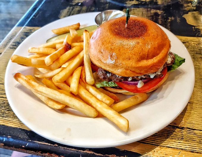 The burger arrives like a proper gentleman—well-dressed, substantial, and surrounded by golden fries that could make a French chef weep with joy.