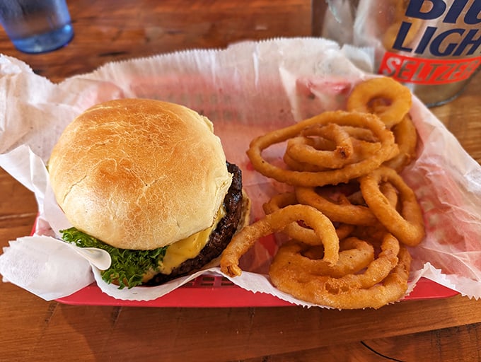 A proper tavern burger doesn't need truffle aioli or artisanal brioche—just quality beef, melty cheese, and those onion rings that shatter with each glorious bite.