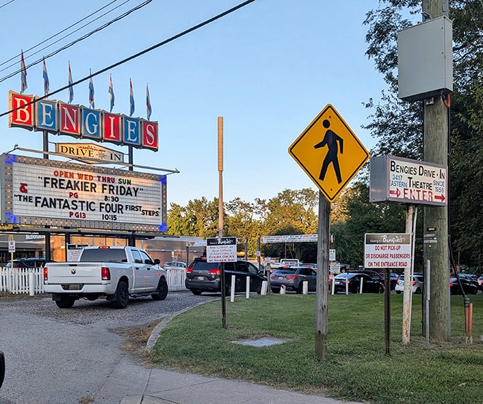 The entrance ritual—cars forming an anticipatory procession toward celluloid dreams. Everyone remembers their first drive-in pilgrimage.