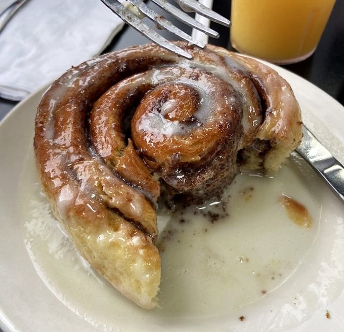The cinnamon roll doesn't merely sit on the plate—it lounges, confident in its gooey, spiraled perfection, daring you to resist its siren call.