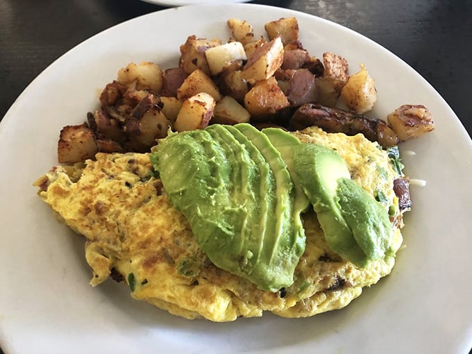 An omelet that's been given the California treatment – avocado slices fanned out like they're auditioning for a food magazine.