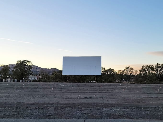 The empty screen against a pristine sky waits patiently for darkness, like a storyteller clearing their throat before beginning an enchanting tale.