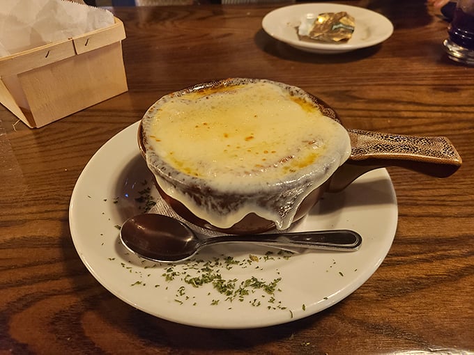 The French onion soup arrives like a warm hug in a crock—a bubbling blanket of melted cheese concealing a rich, beefy broth that's worth every potential chin dribble.