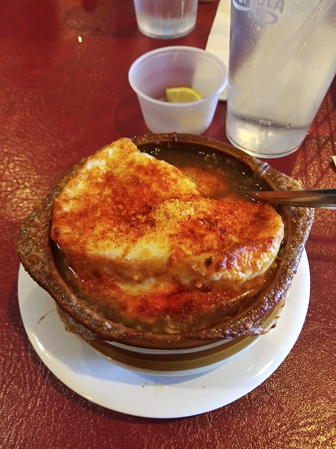French onion soup done right—a bubbling cauldron of savory broth beneath a golden cheese cap that stretches with each spoonful like nature intended.