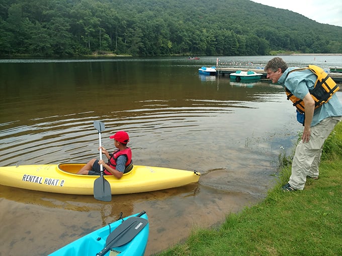Kayaking 101: Child learns the paddle basics while an adult supervisor ensures safety first at Poe Lake's calm waters.