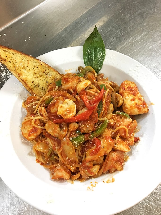 Pasta that would make your Italian grandmother nod in approval—vibrant, saucy, and adorned with a garlic bread sidekick that deserves its own fan club.