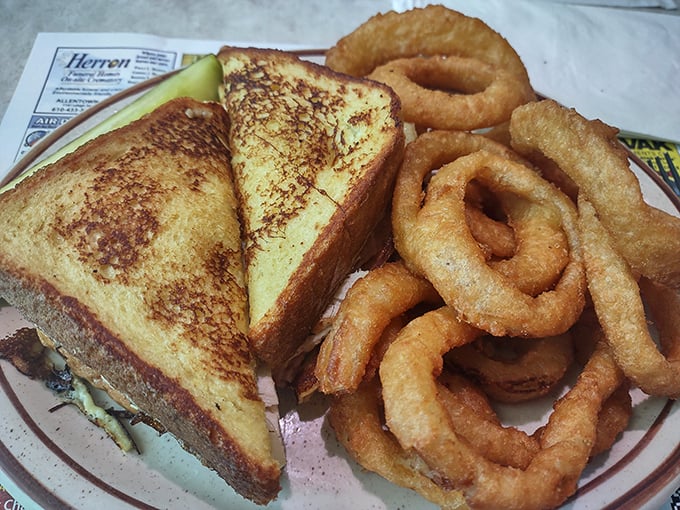 The patty melt—diner royalty on a plate. Golden-grilled bread embracing melted cheese and a juicy patty, with onion rings that deserve their own fan club.
