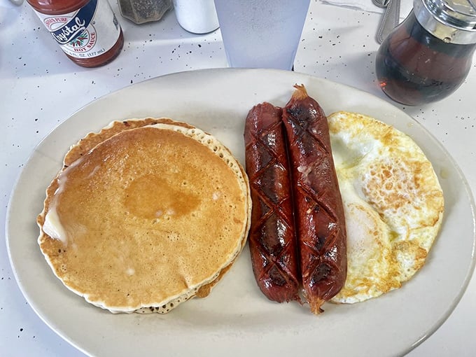 The breakfast holy trinity – golden pancake, perfectly cooked eggs, and those legendary smoked sausages glistening with just the right amount of char.
