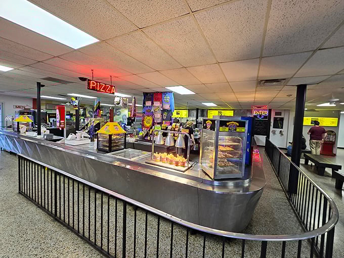 Stainless steel counters gleaming under "PIZZA" in neon red. The concession stand: where movie night meets comfort food paradise.