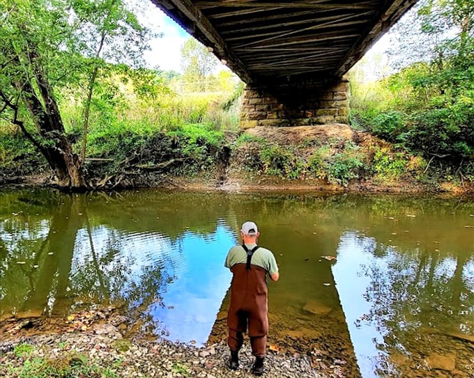 Peaceful fishing moments under the covered bridge bring calm reflections, with nature’s beauty surrounding the gentle flow of the stream.