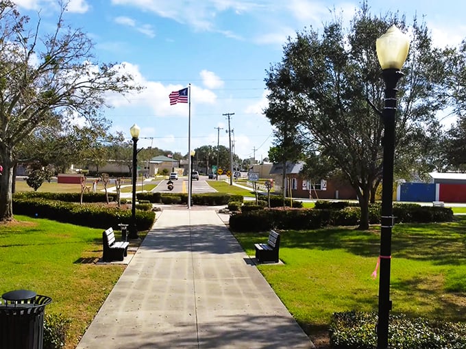 A charming view of Lake Placid’s welcoming park, complete with benches, bright green lawns, and the American flag.
