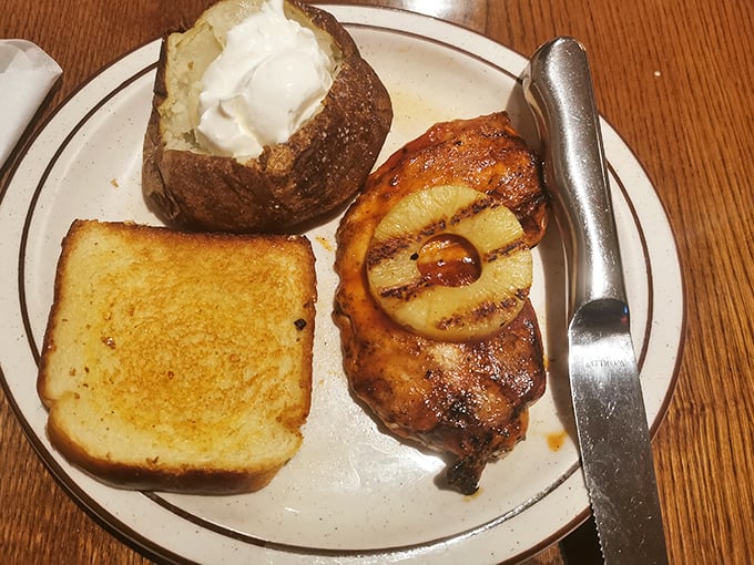 BBQ chicken with a charred pineapple ring and a loaded baked potato—proof that sometimes the simple classics deliver the most satisfaction.